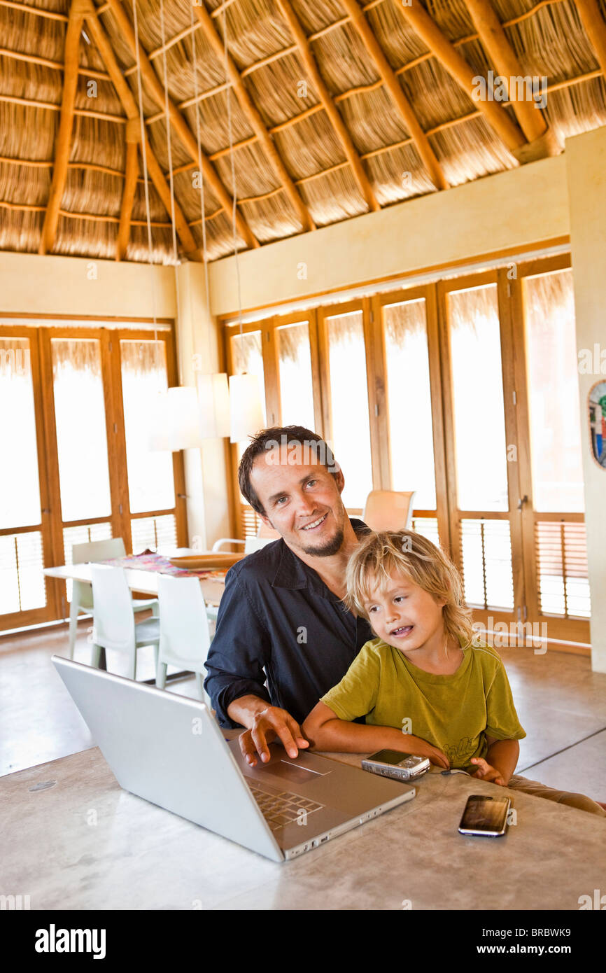 man working on laptop with child on lap Stock Photo - Alamy