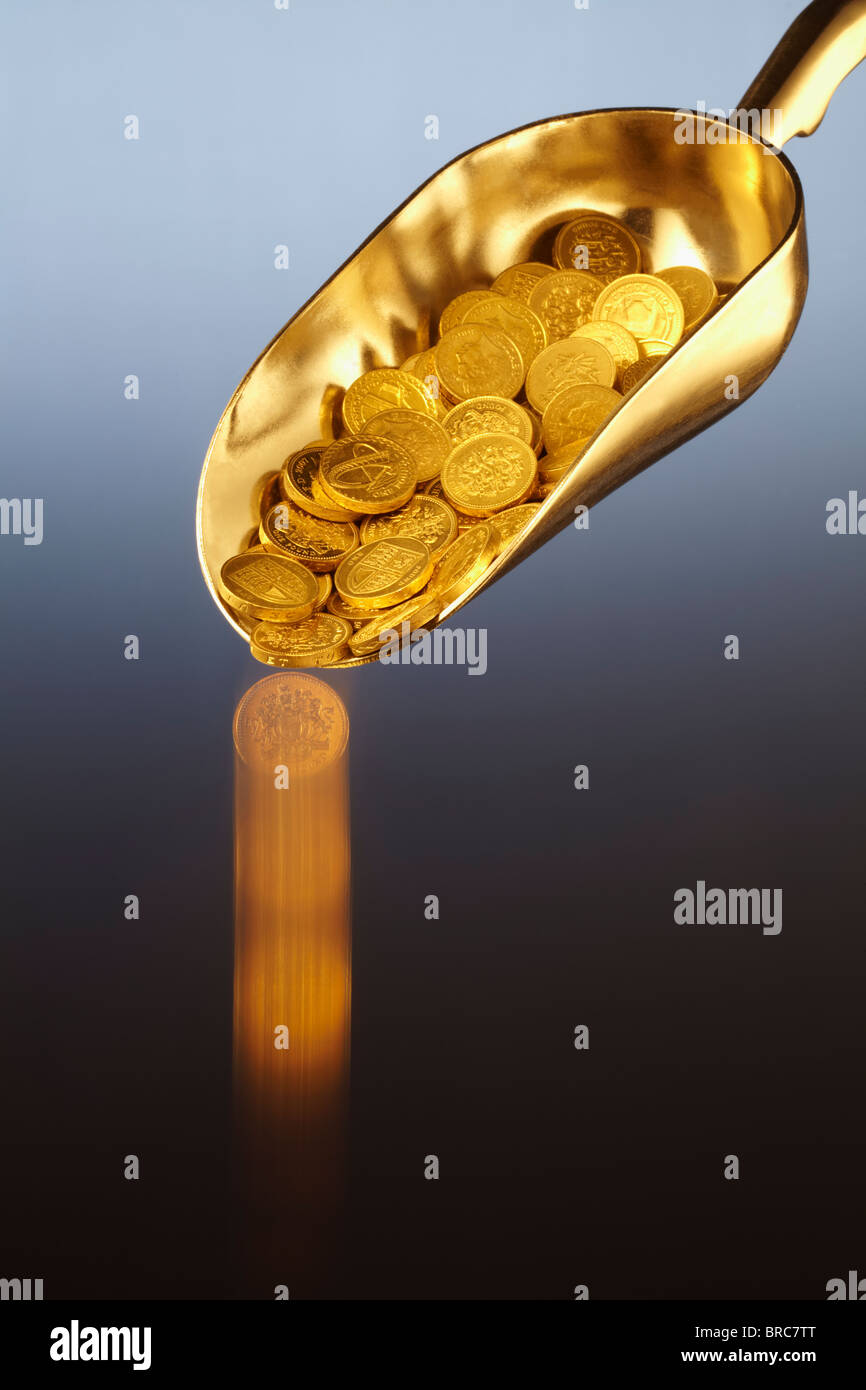 Golden scoop of money with falling pound coin Stock Photo - Alamy