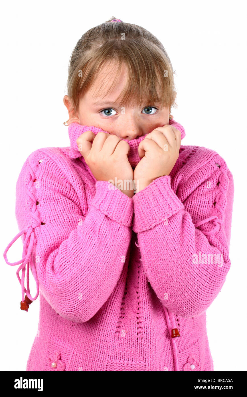 Small girl in pink sweater feeling cold embracing herself looking at ...
