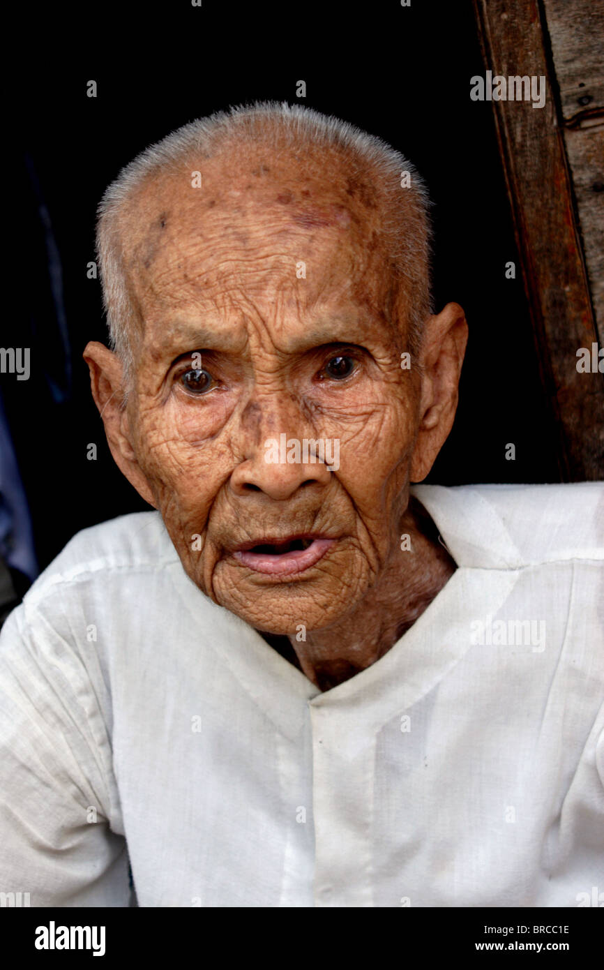 An elderly female Buddhist monk sits at the entrance to her living ...