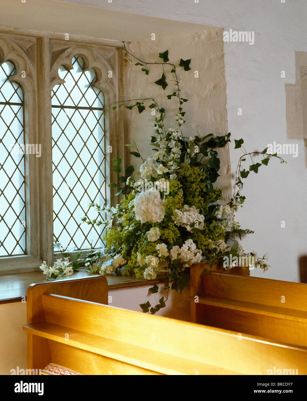 White floral arrangement on windowsill of Gothic lattice window in ...