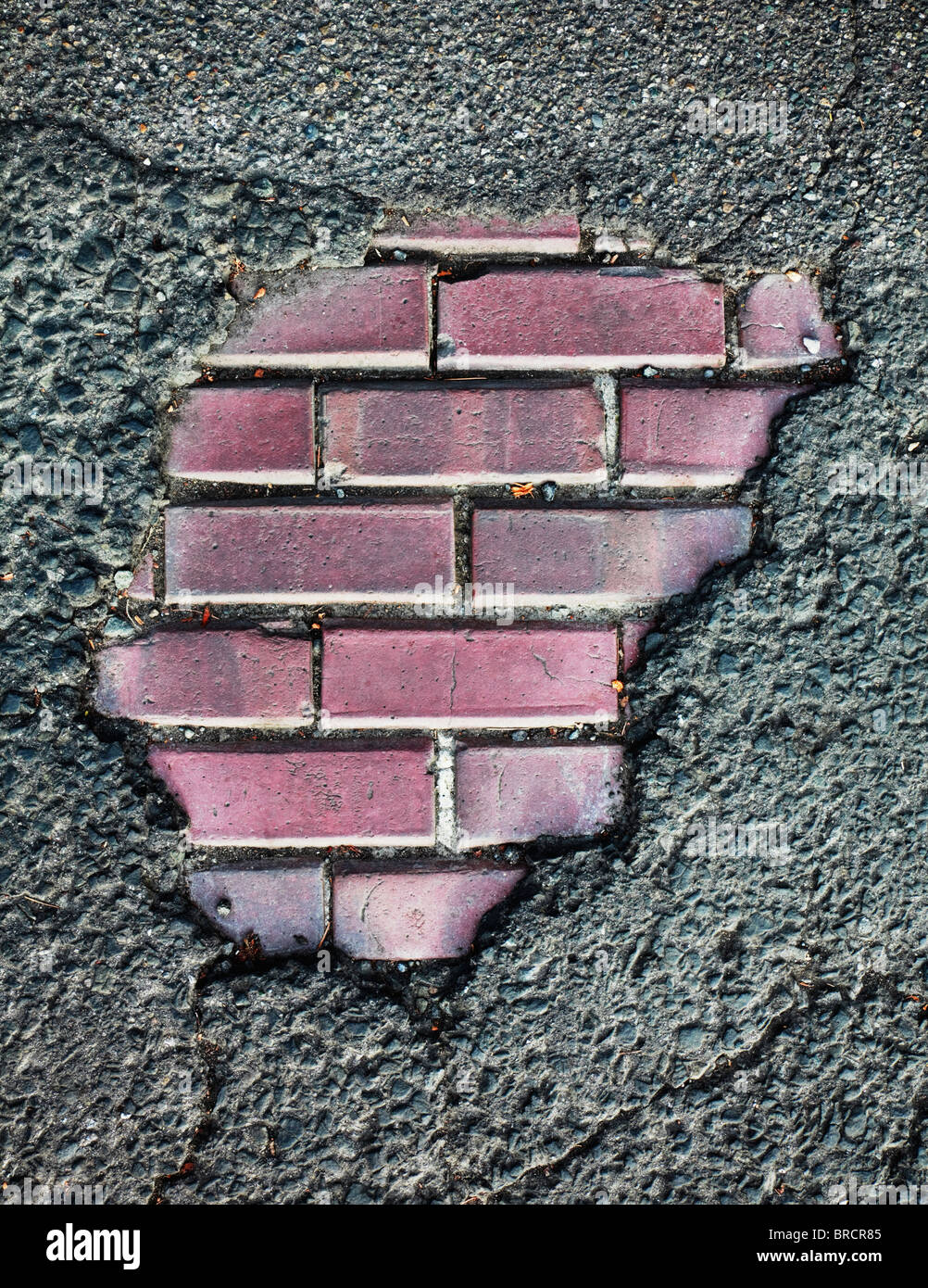 brick showing through hole in asphalt paved street Stock Photo - Alamy
