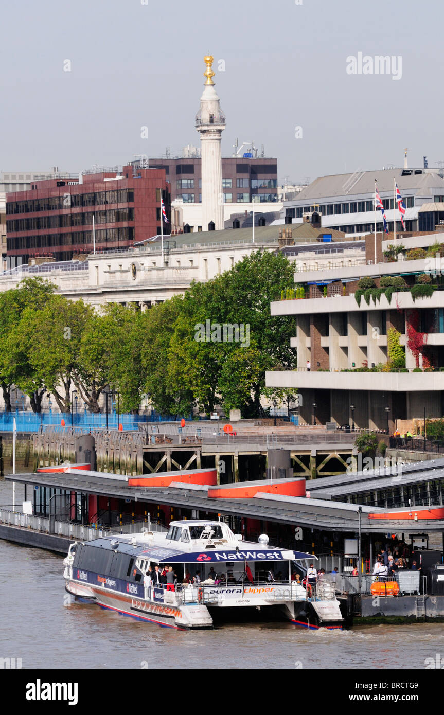 A Thames Clippers riverbus at Tower Pier, with The Great Fire Monument ...