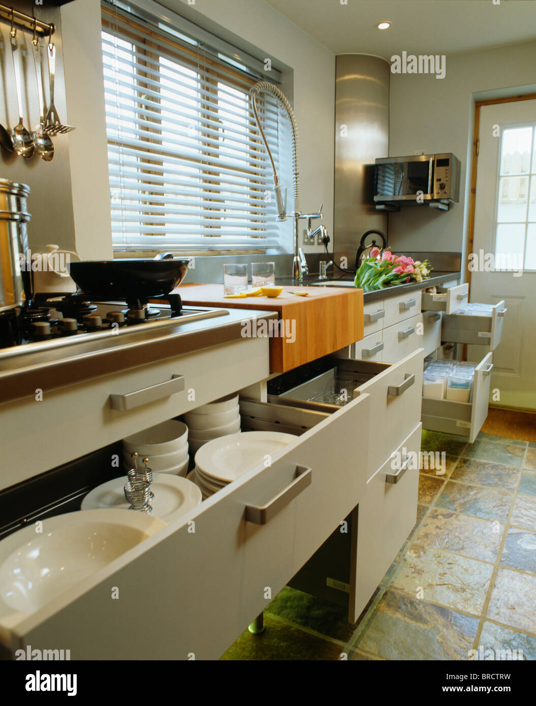 Close-up of large open storage drawers with white crockery in modern ...