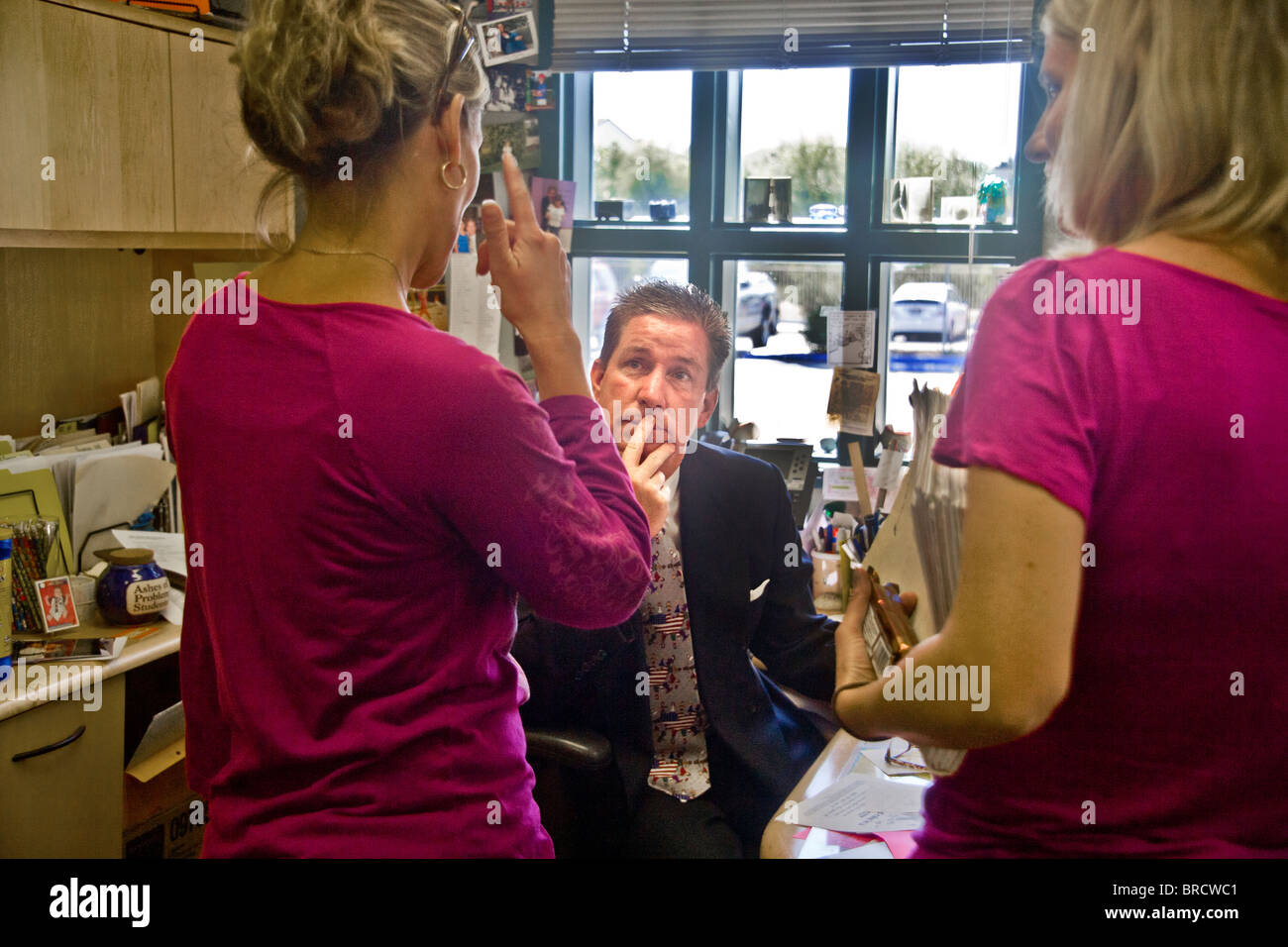 A concerned Southern California school principal meets with two women teachers in his office ...