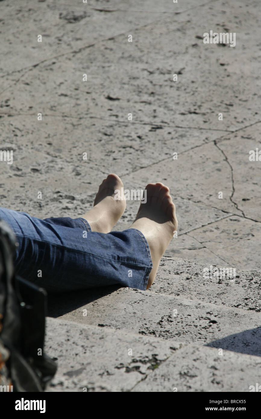 person feet legs sitting on steps in street in town take off shoes ...