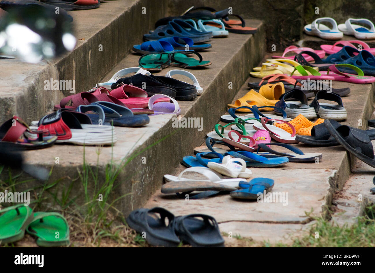 Plastic sandals on the concrete stairs of a Buddhist temple in Thailand ...