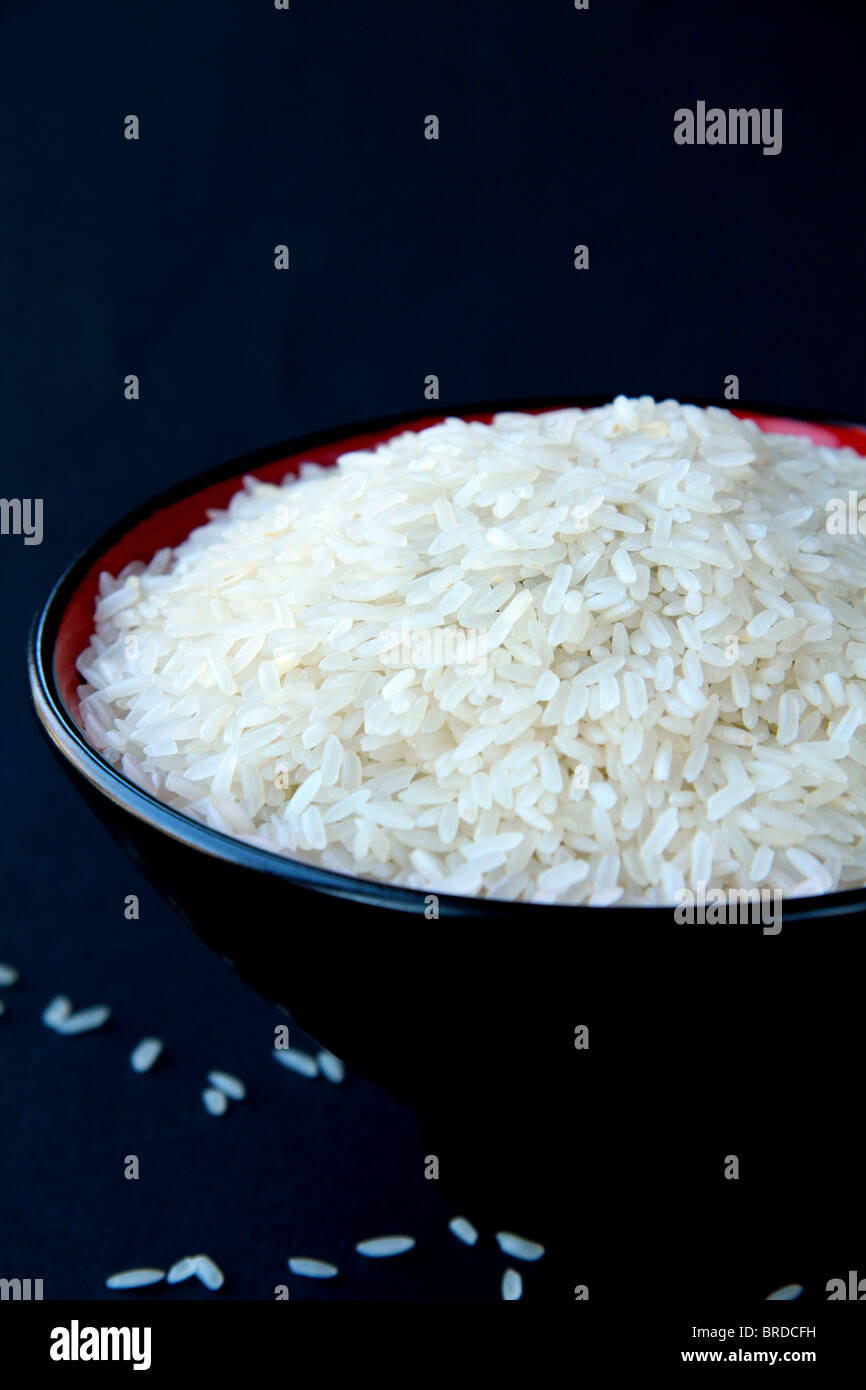 White rice in a cup of black on black background Stock Photo - Alamy