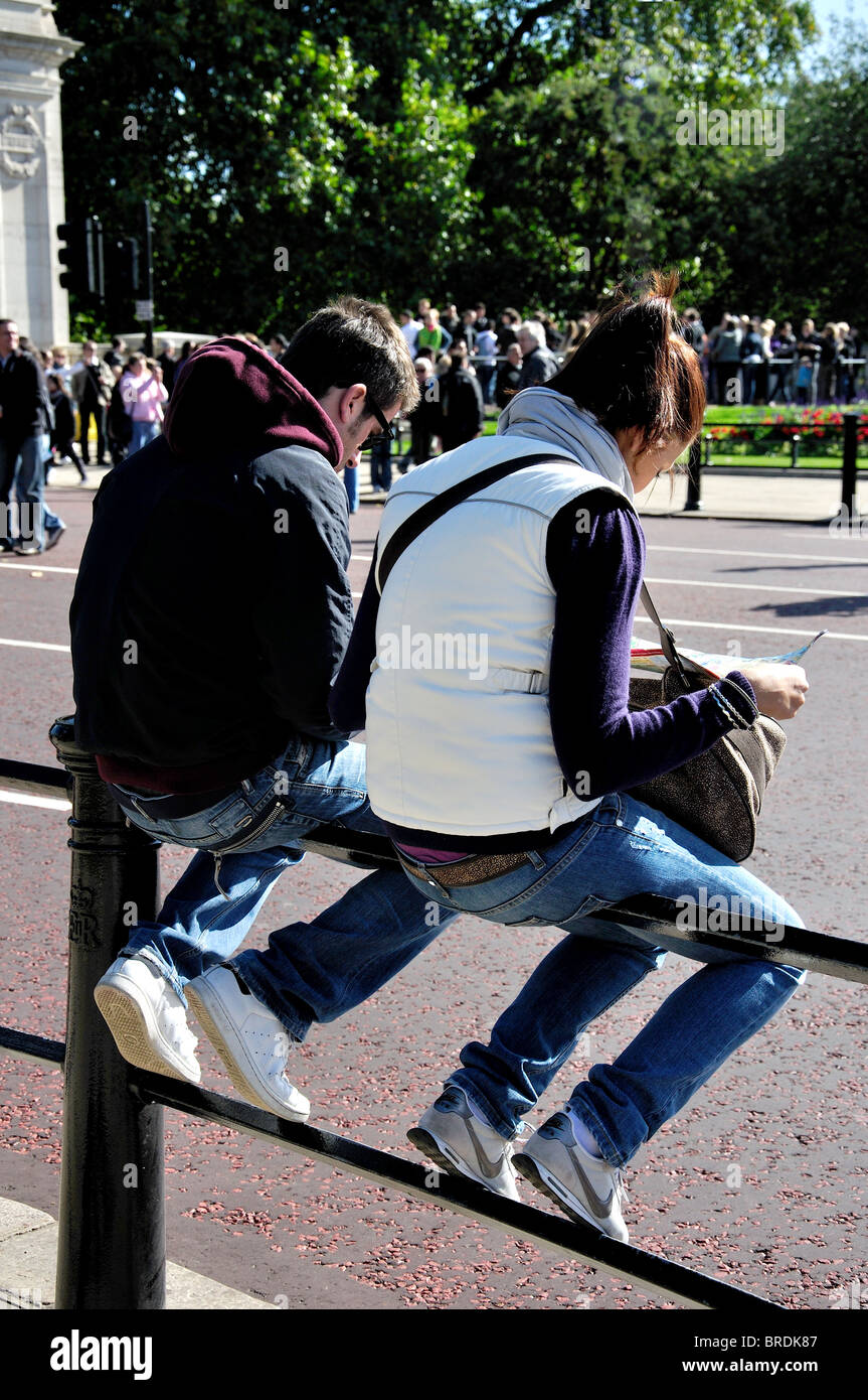 Young couple sitting on railings by Buckingham Palace, City of ...