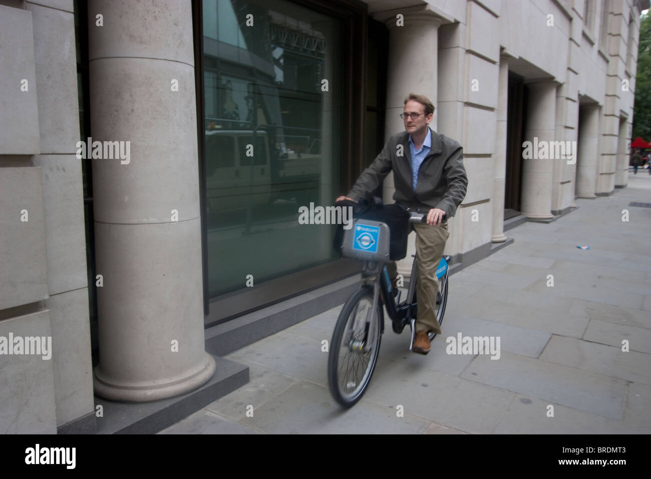Cyclist riding a Boris Bike (TfL hire bike) on the pavement, sponsored ...
