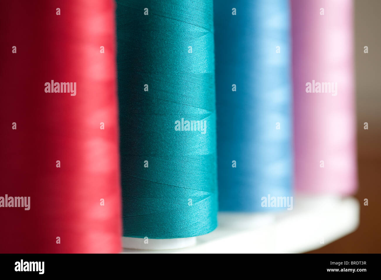Multicolored spools of thread on a spindle on a serger sewing machine ...