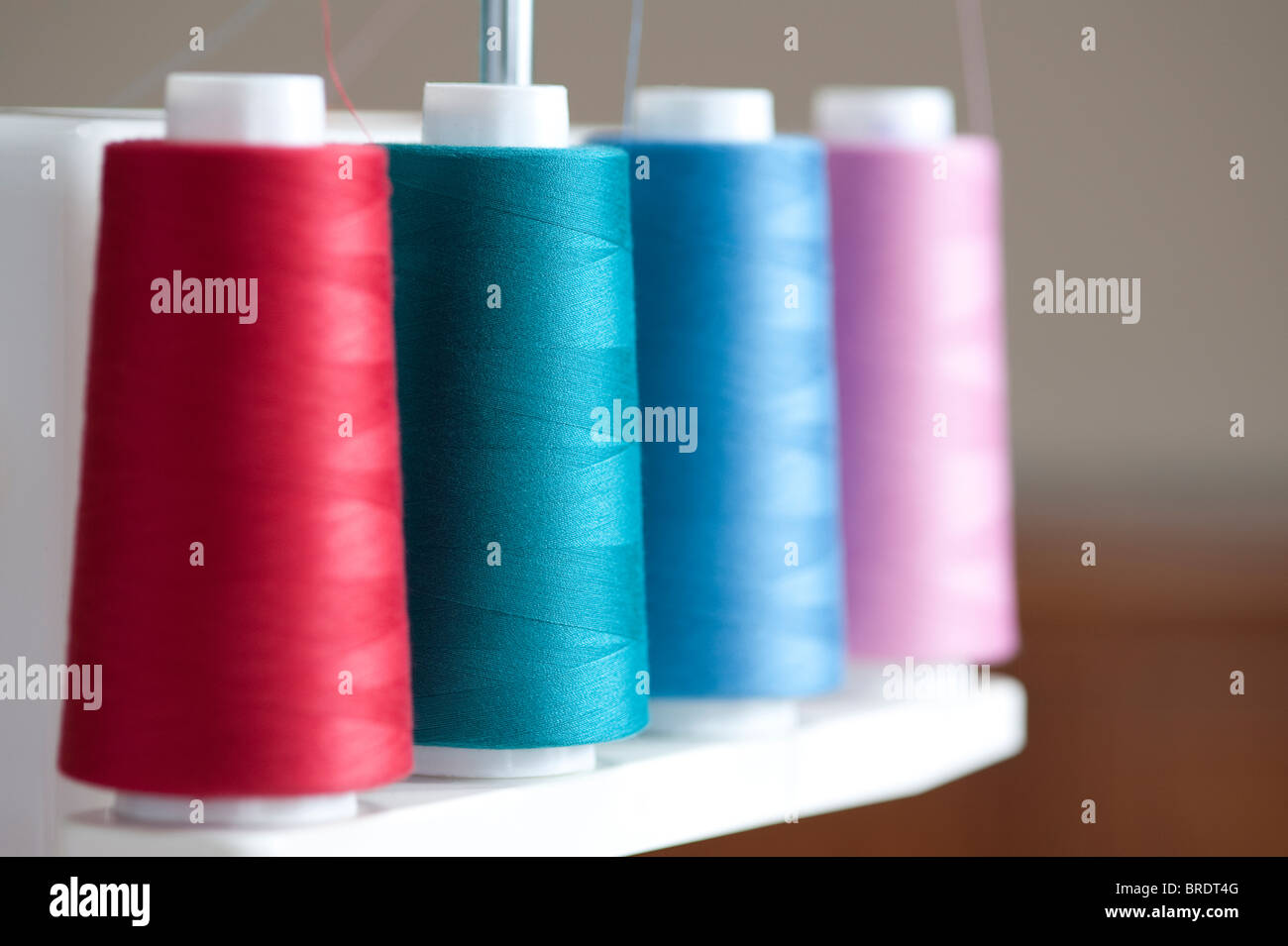 Multicolored spools of thread on a spindle on a serger sewing machine ...