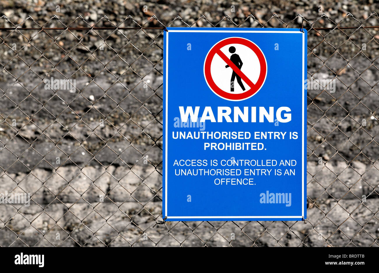 A warning sign on a wire fence with blue background and a black figure ...