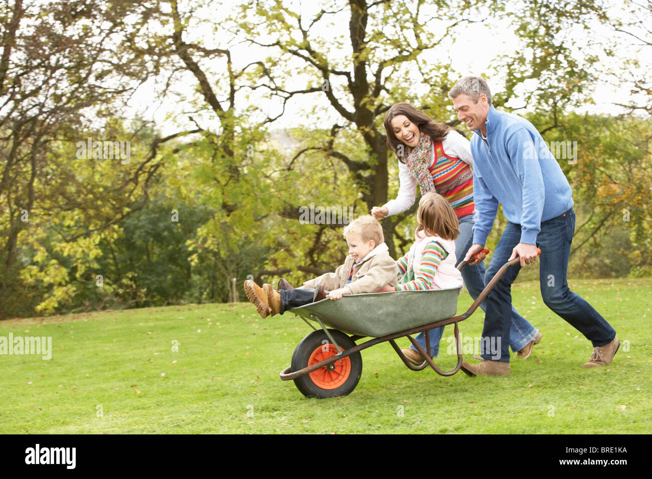 Parents Giving Children Ride In Wheelbarrow Stock Photo - Alamy