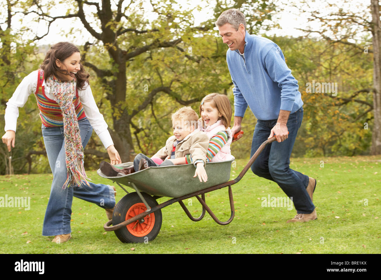 Parents Giving Children Ride In Wheelbarrow Stock Photo - Alamy