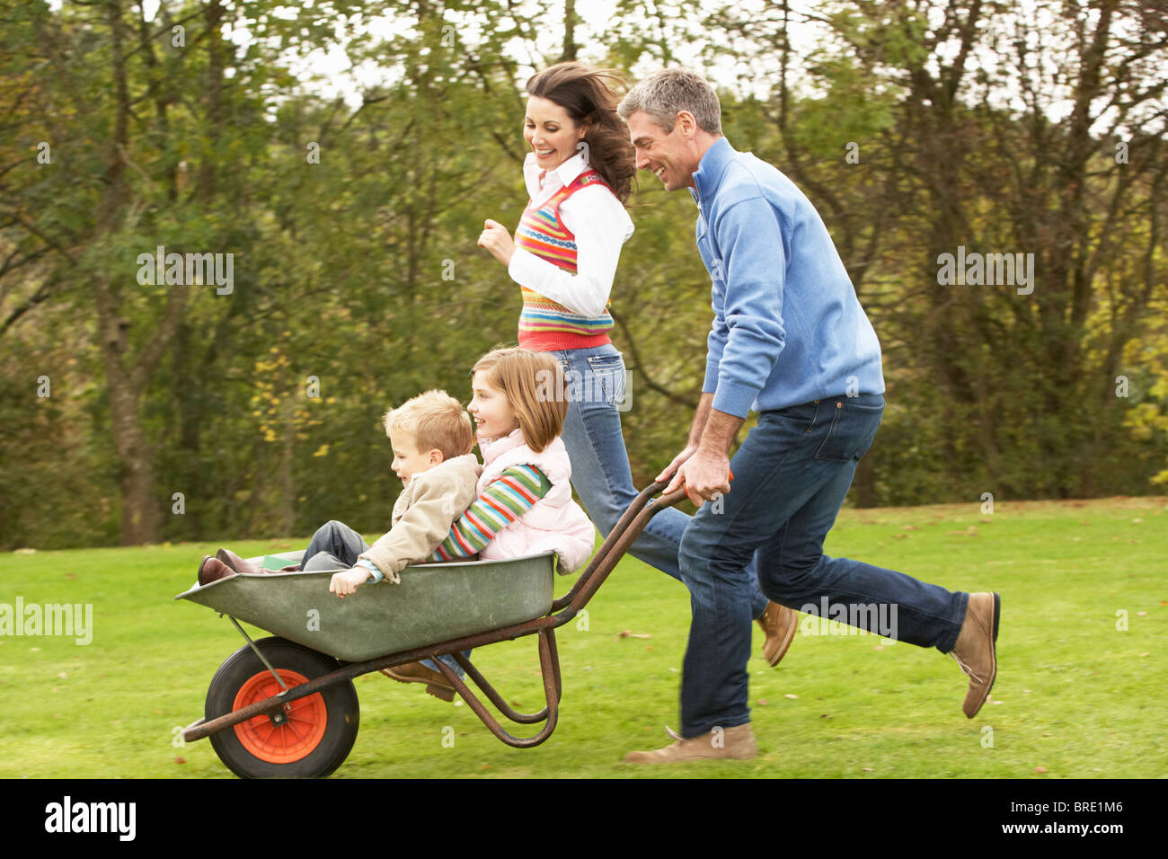Parents Giving Children Ride In Wheelbarrow Stock Photo - Alamy