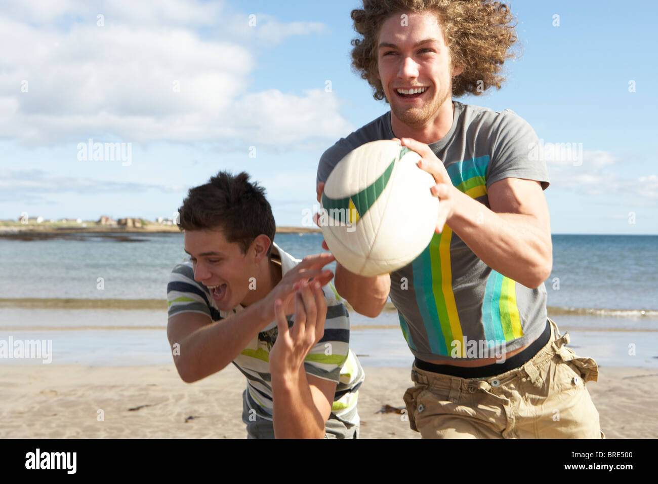 Two Teenage Boys Playing Rugby On Beach Together Stock Photo - Alamy