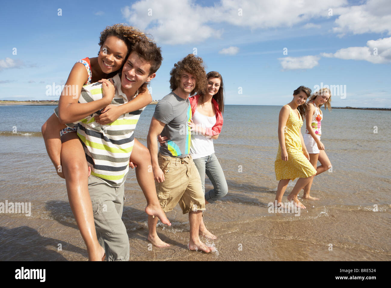 Group Of Young Friends Walking Along Summer Shoreline Stock Photo - Alamy