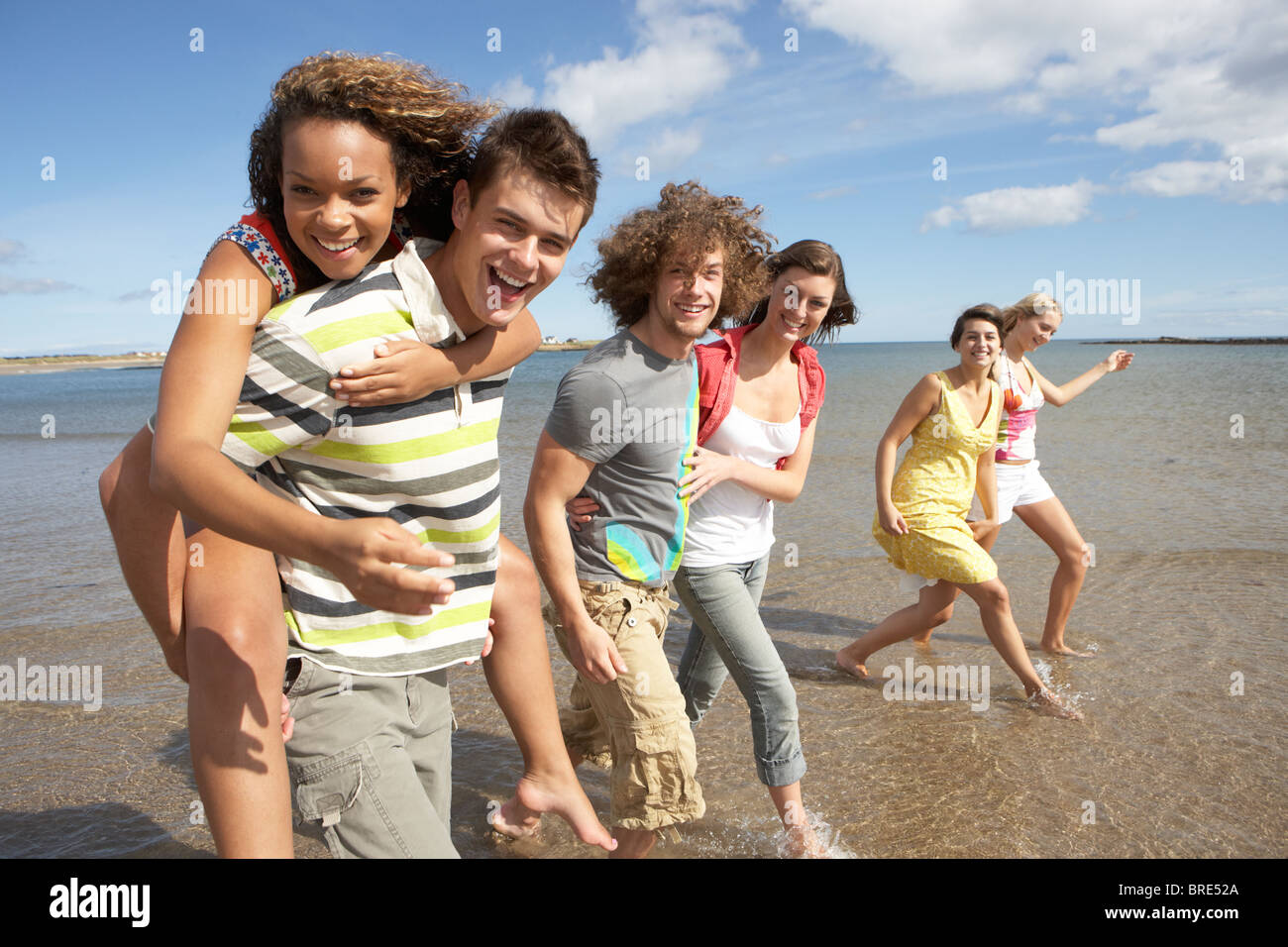 Group Of Young Friends Walking Along Summer Shoreline Stock Photo - Alamy