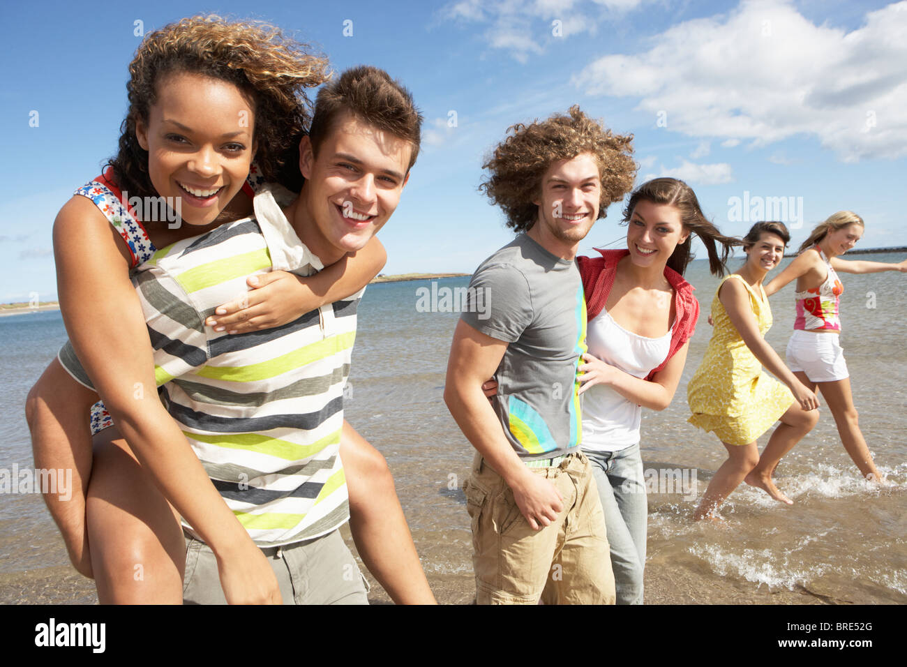 Group Of Young Friends Walking Along Summer Shoreline Stock Photo - Alamy