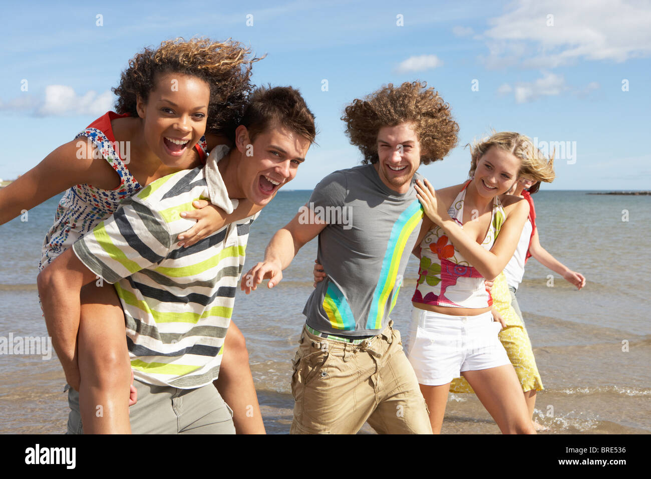 Group Of Young Friends Walking Along Summer Shoreline Stock Photo - Alamy
