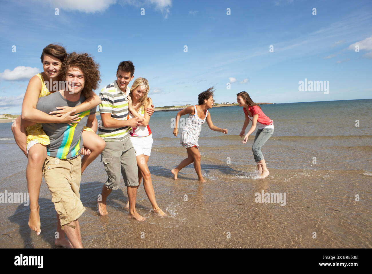 Group Of Young Friends Walking Along Summer Shoreline Stock Photo - Alamy