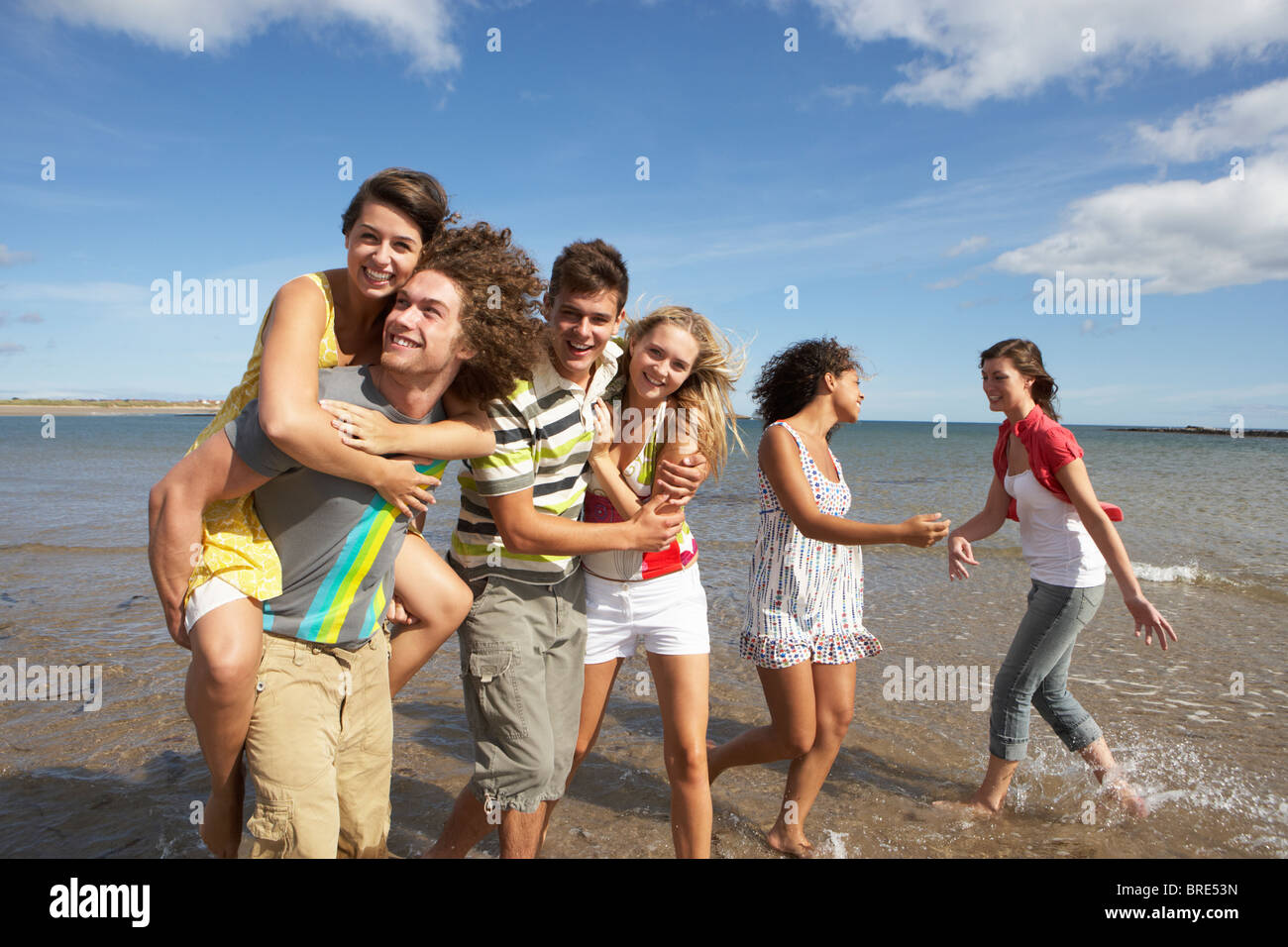 Group Of Young Friends Walking Along Summer Shoreline Stock Photo - Alamy