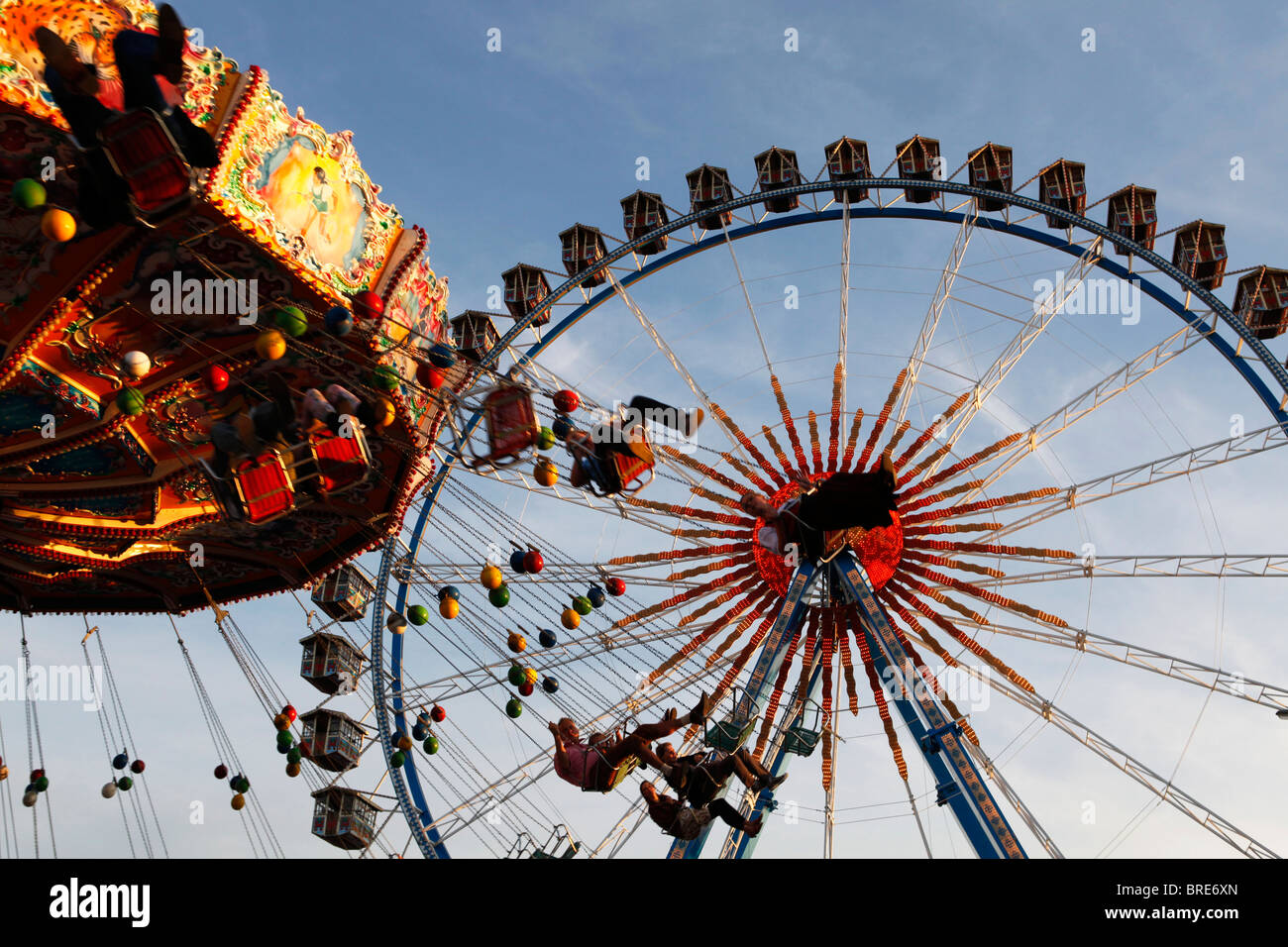 People swing on a carousel in front of a big wheel Stock Photo - Alamy