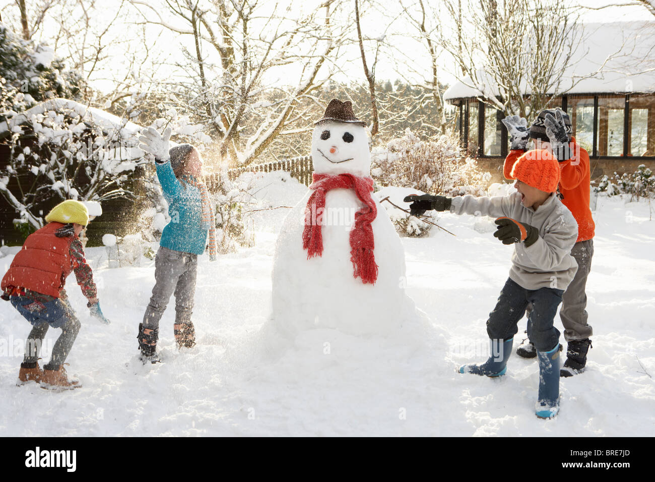 Mother And Children Building Snowman In Garden Stock Photo - Alamy
