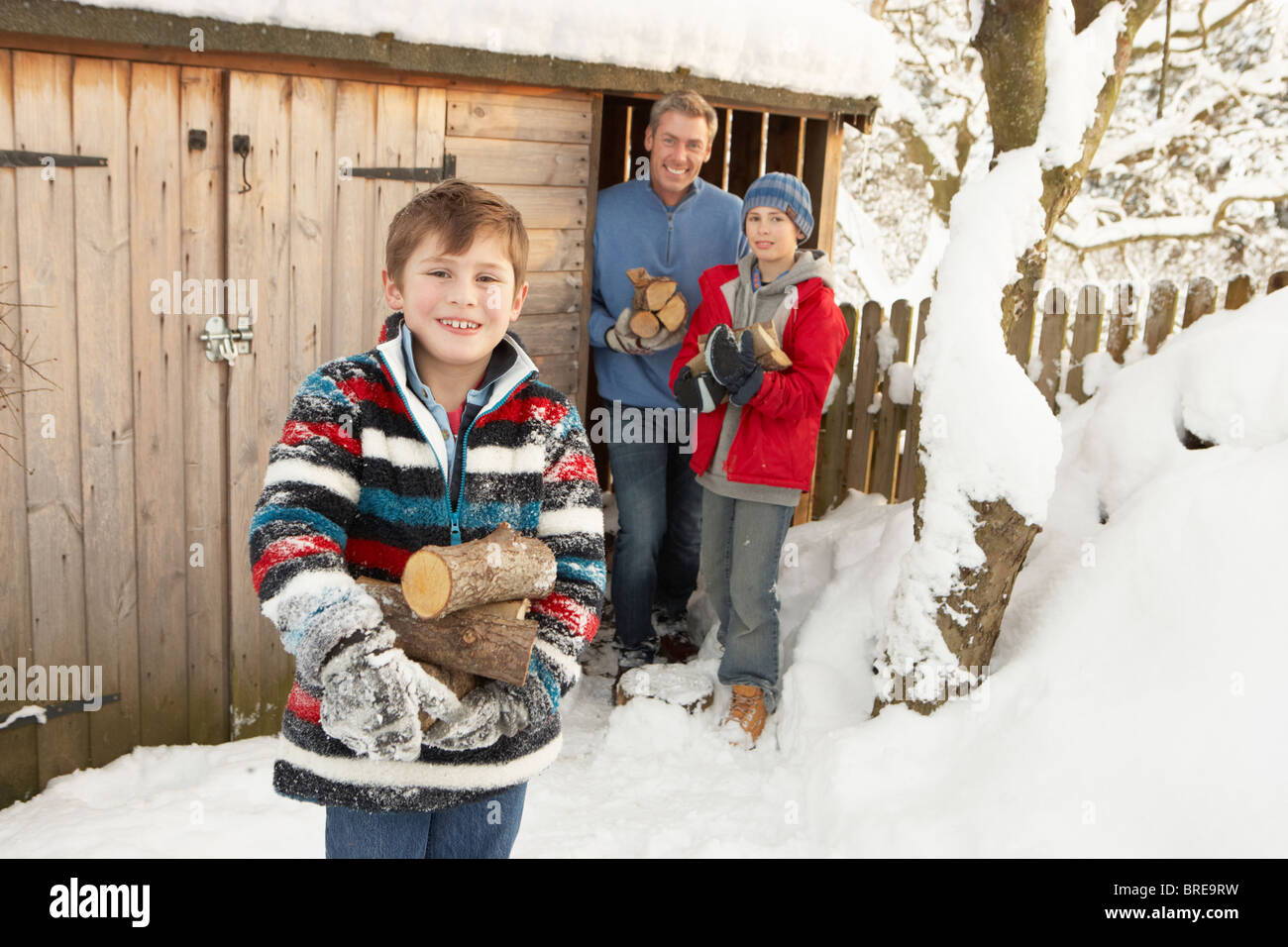 Family Collecting Logs From Wooden Store In Snow Stock Photo - Alamy