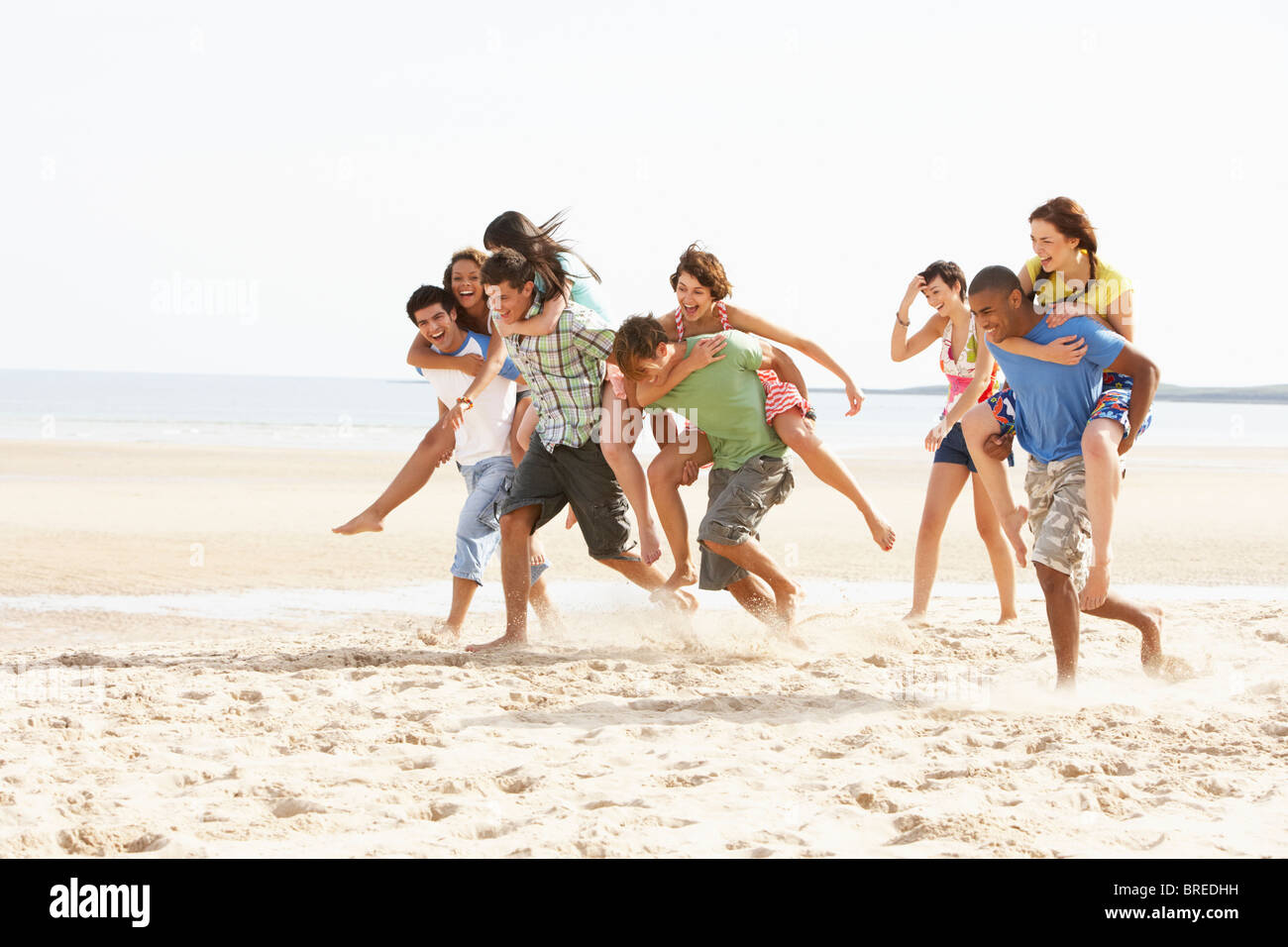 Group Of Friends Running Along Beach Together Stock Photo - Alamy