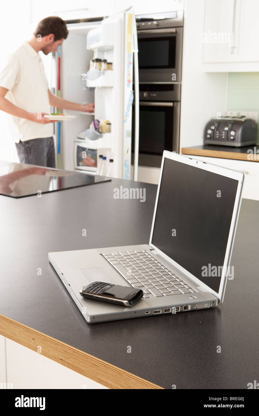 Young Man Fixing Snack In Kitchen With Laptop In Modern Kitchen Stock ...