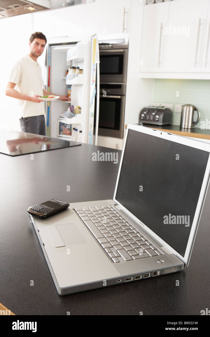Young Man Fixing Snack In Kitchen With Laptop In Modern Kitchen Stock ...
