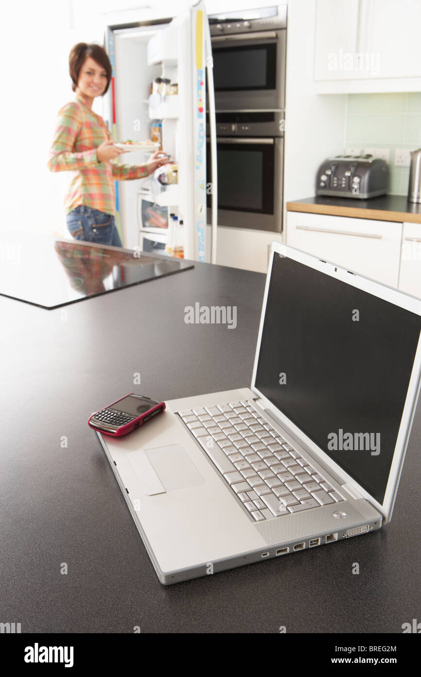 Young Woman Fixing Snack In Kitchen With Laptop In Modern Kitchen Stock ...