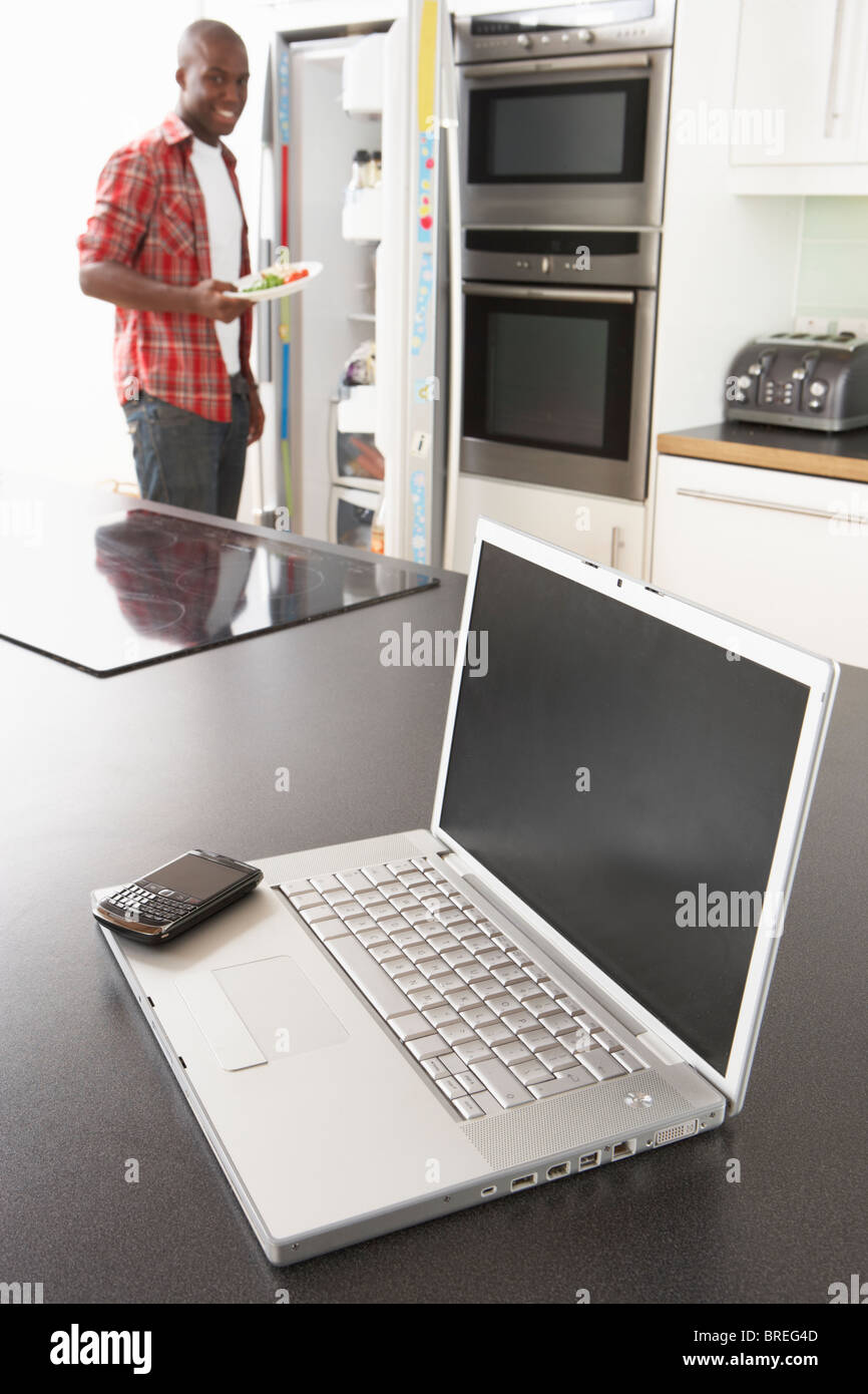 Young Man Fixing Snack In Kitchen With Laptop In Modern Kitchen Stock ...