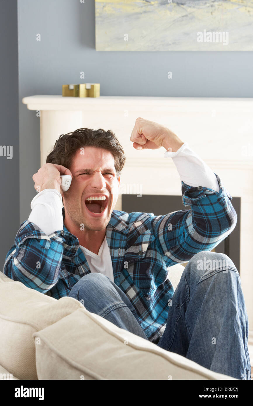 Excited Man Sitting On Sofa At Home Talking On Phone Stock Photo - Alamy