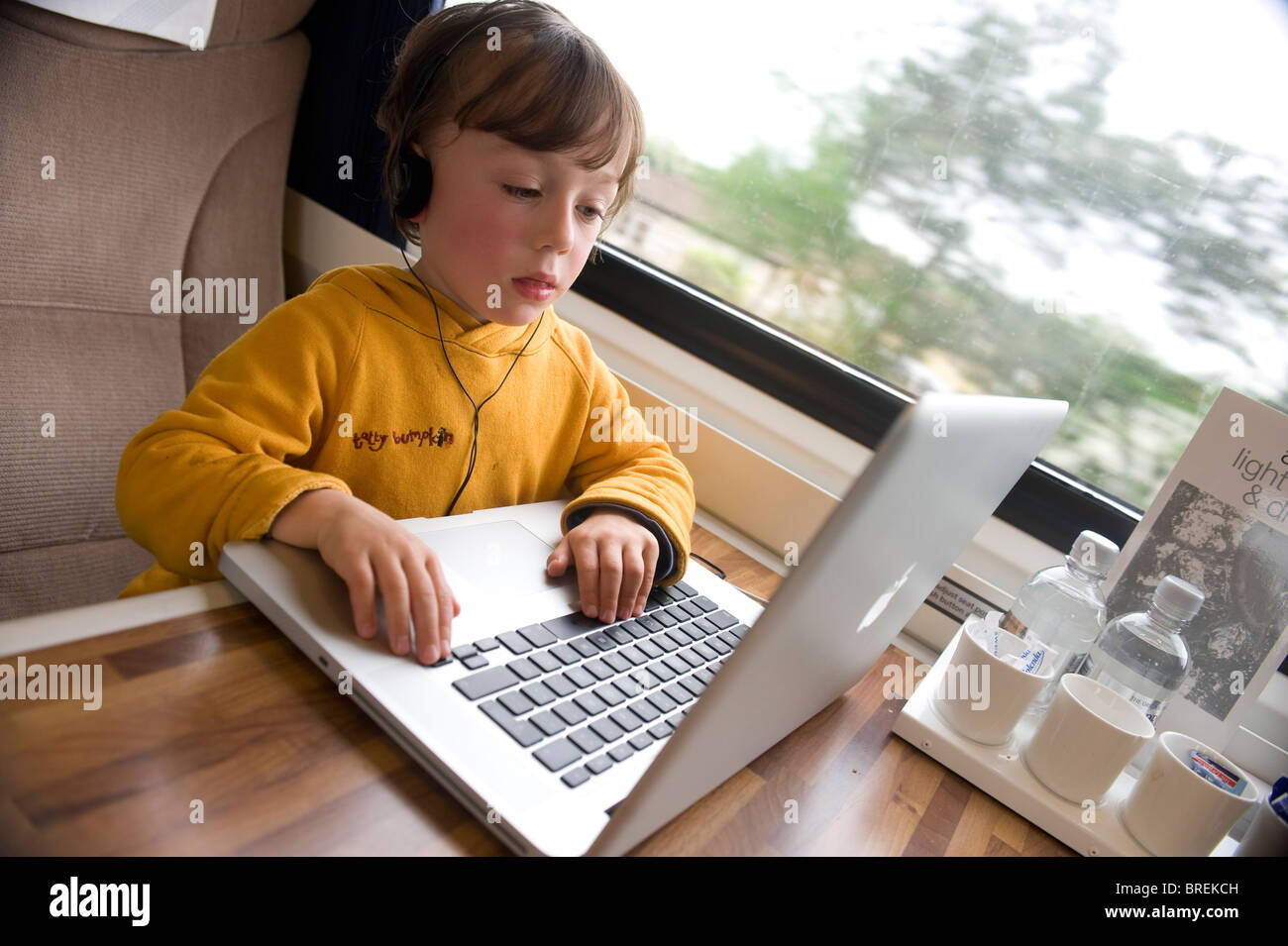 young boy playing games on an apple mac computer on a train journey ...