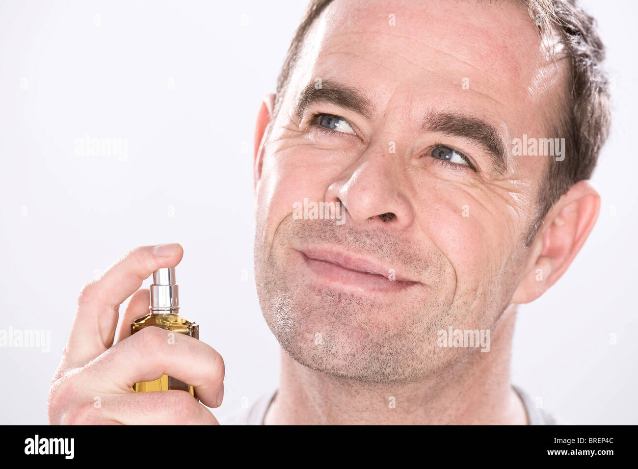 Smiling man putting on perfume Stock Photo - Alamy