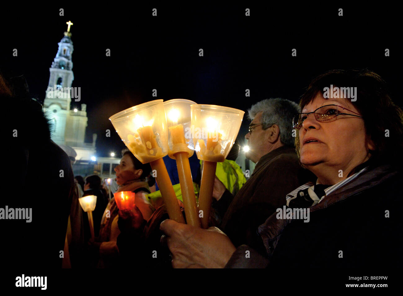 A pilgrim holds candles during the nighttime procession at the Our Lady ...