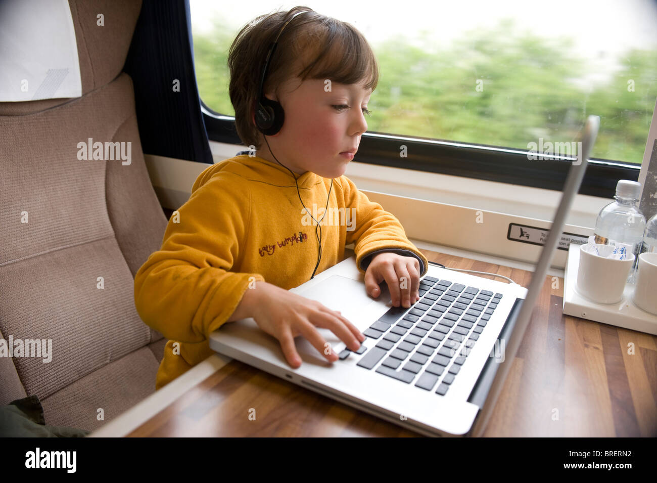 young boy playing games on an apple mac computer on a train journey ...