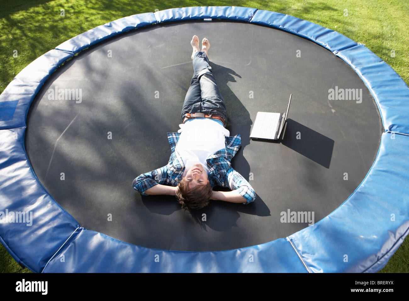 Young Man Relaxing On Trampoline With Laptop Stock Photo - Alamy