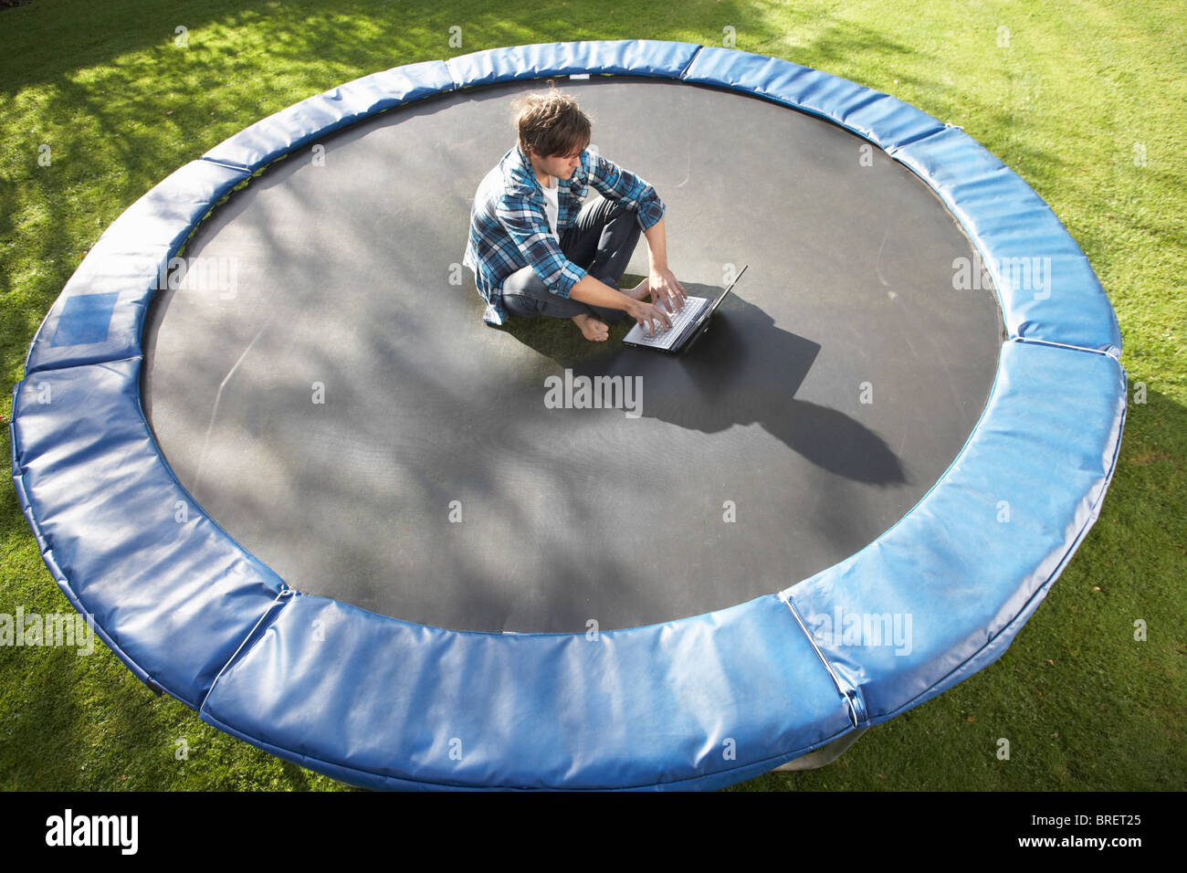 Young Man Relaxing On Trampoline With Laptop Stock Photo - Alamy
