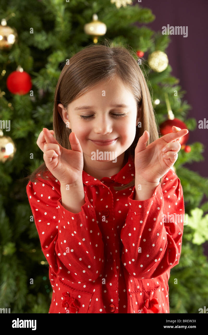 Young Girl Crossing Fingers In Front Of Christmas Tree Stock Photo - Alamy