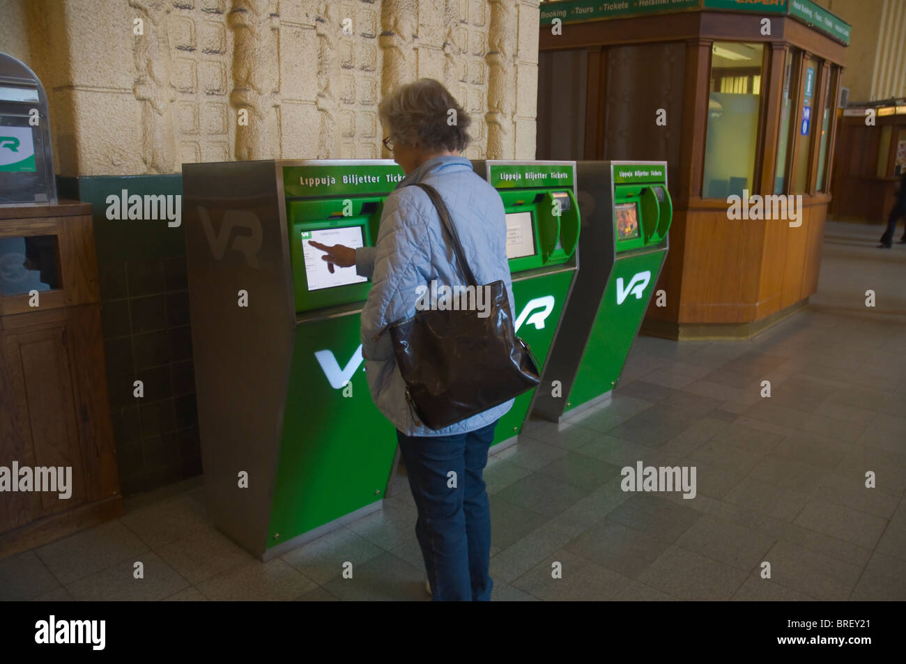 Senior woman using automatic ticket vending machine at train station ...