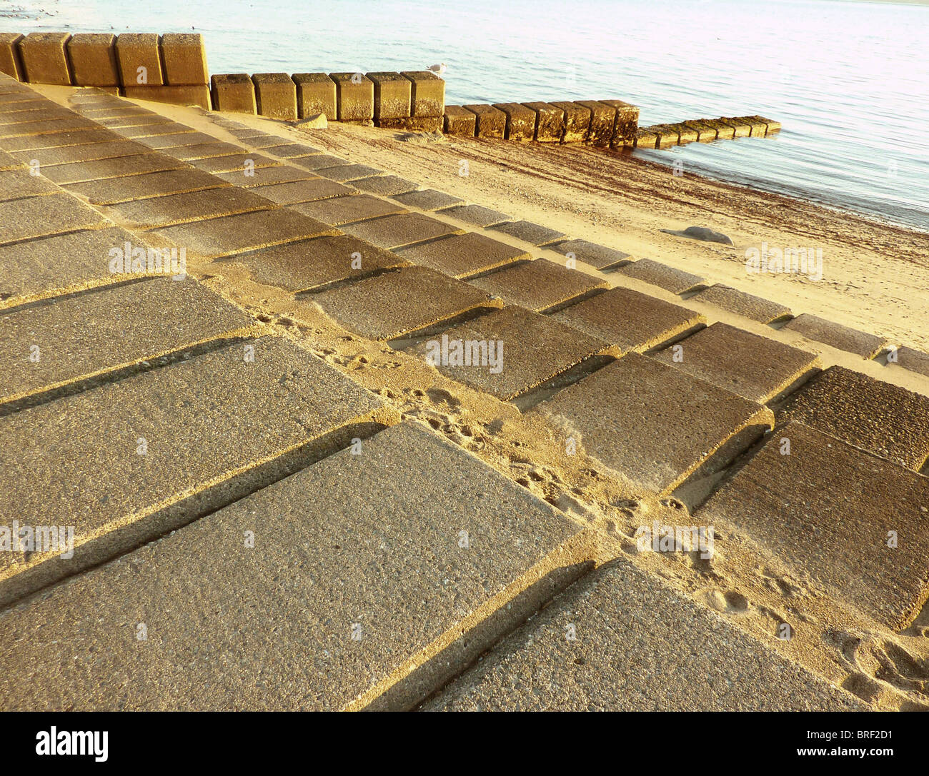 Beachsand on wide stone slab stairway leading into calm ocean. West ...