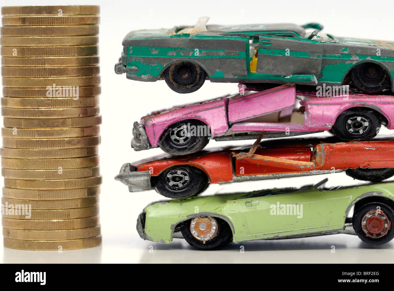 Broken miniature cars and a stack of coins, symbolic picture for ...