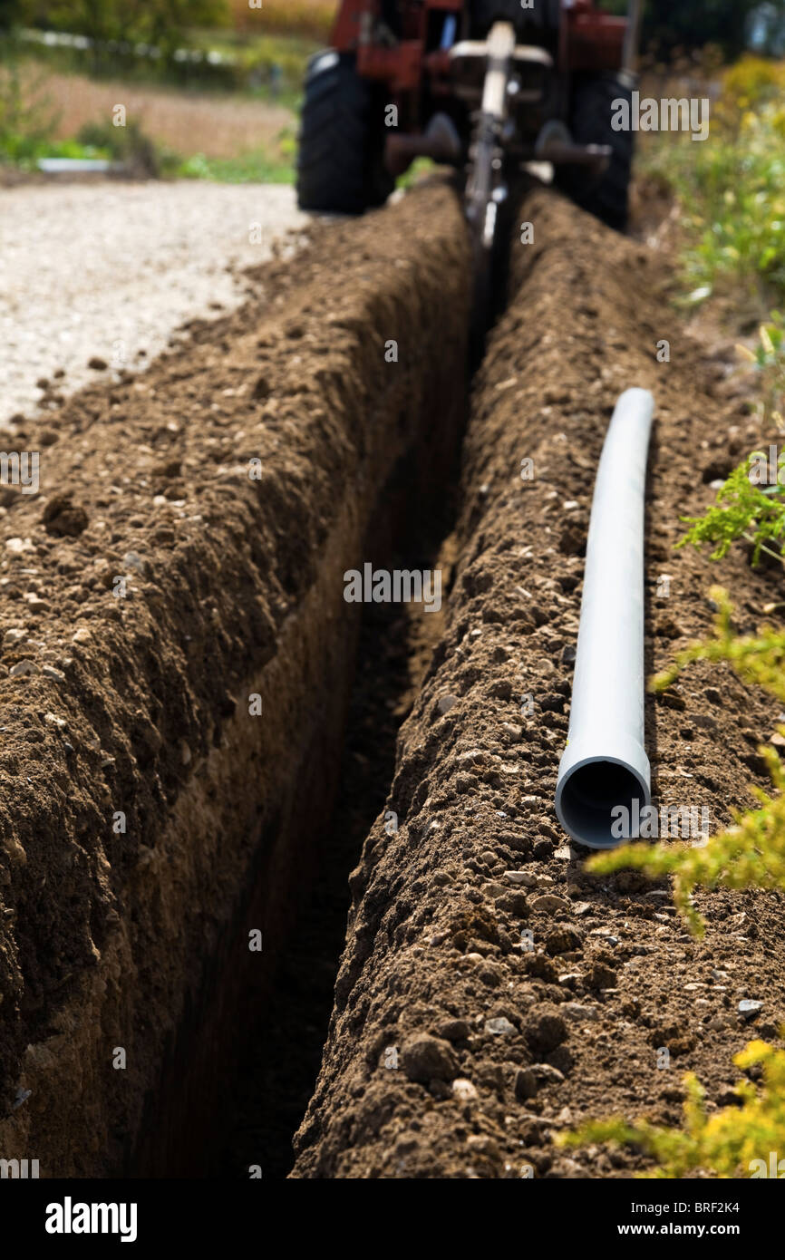 Trencher in action - focus on the pvc conduit Stock Photo - Alamy