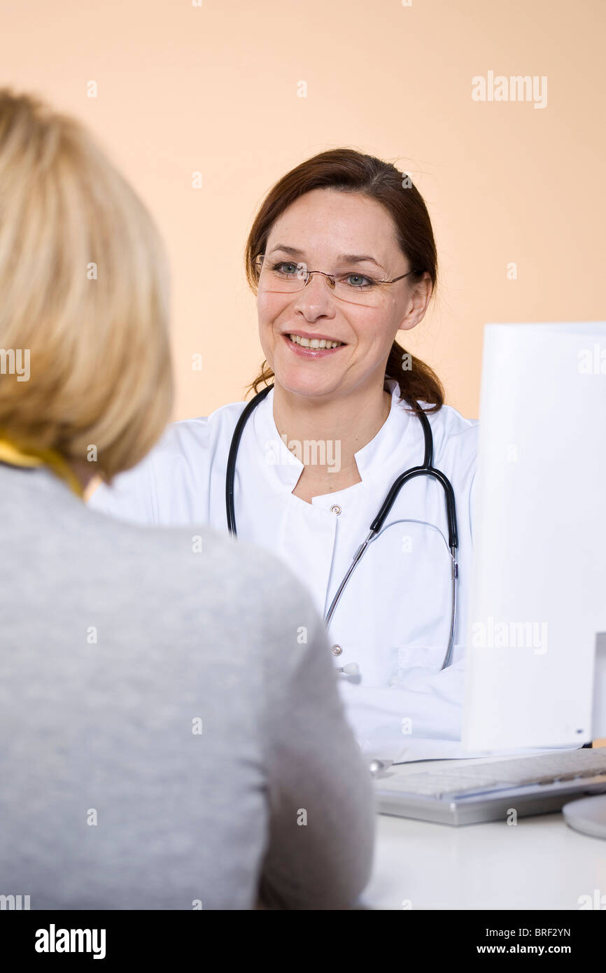 Doctor sitting at a desk, talking to a patient Stock Photo - Alamy