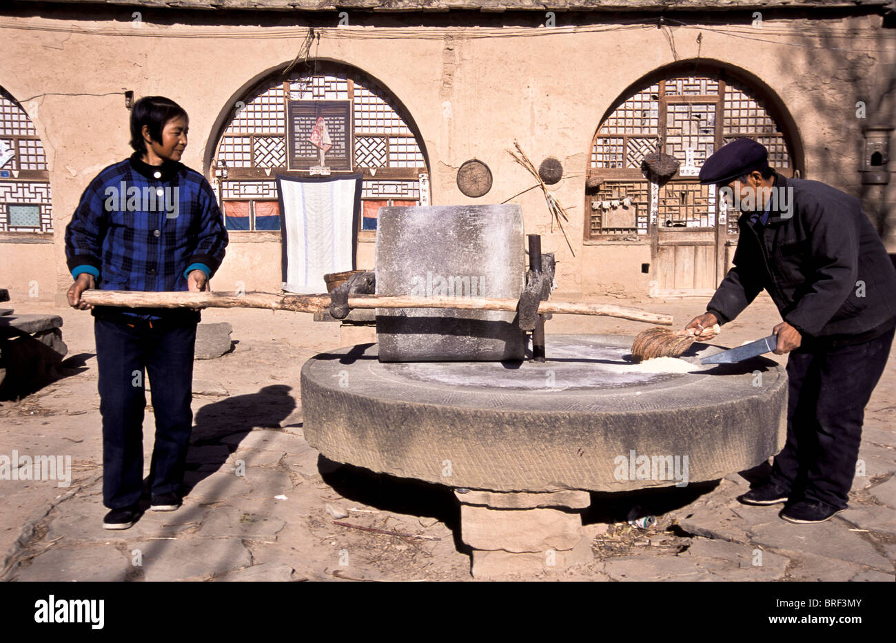 Chang Lin and Du Mei mill corn in their courtyard with their Cave house ...