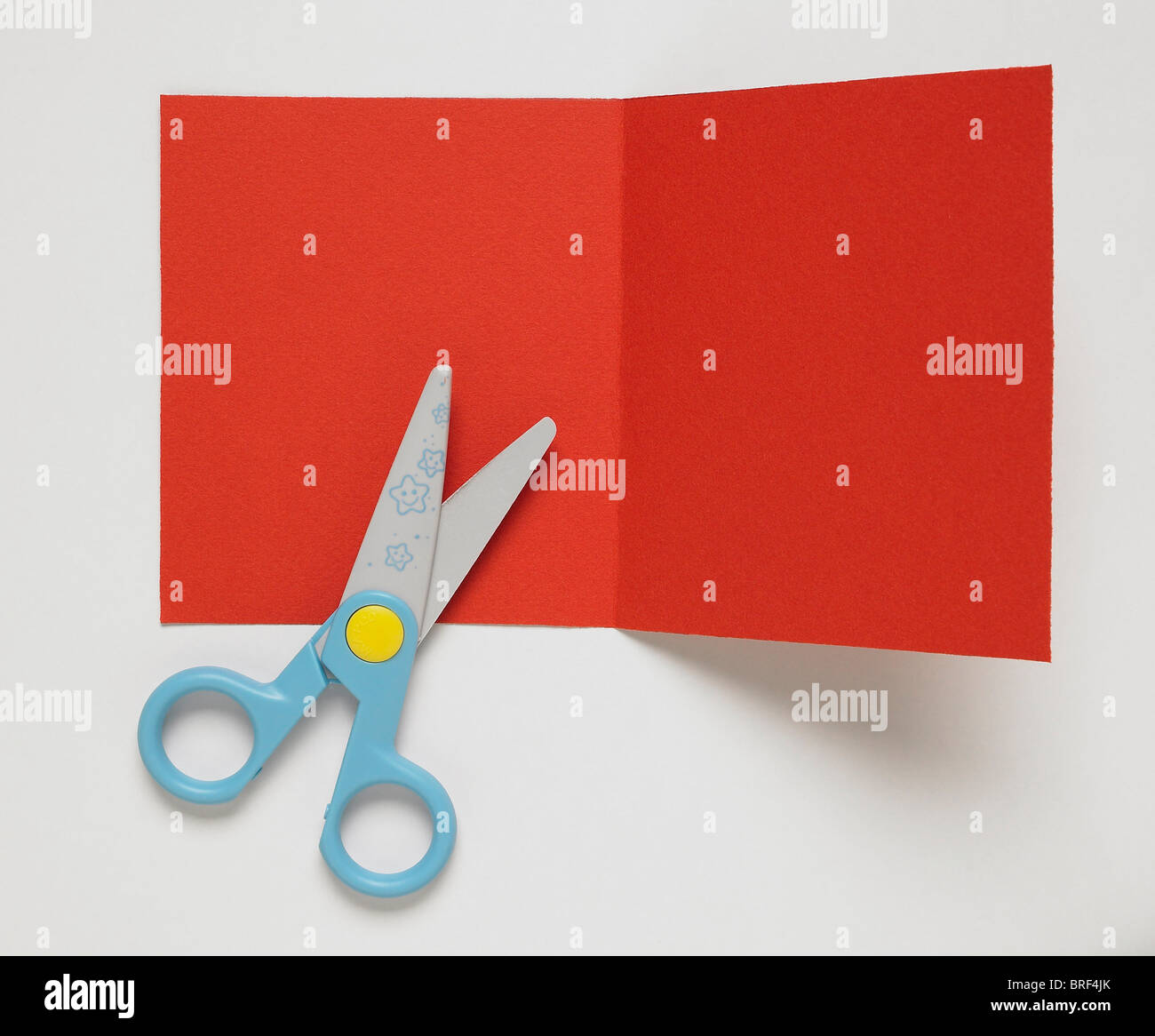 Sheet of red card with crease folded along centre, blue handled ...